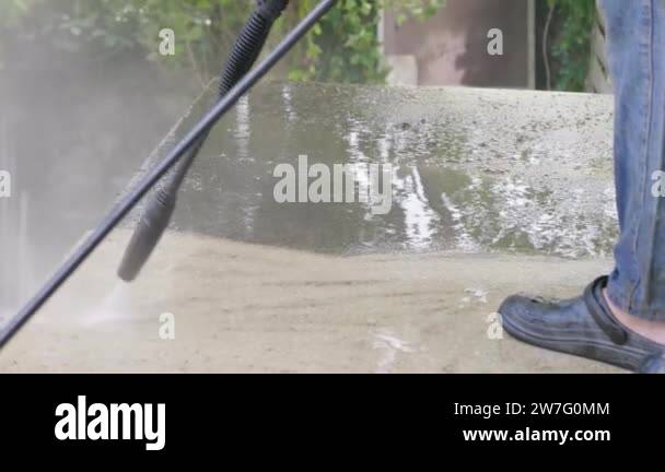 Close up view person with high pressure jet gun spray water to ground ...