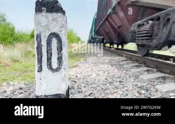 Concrete mark on railroad, freight train carriages pass along rails ...
