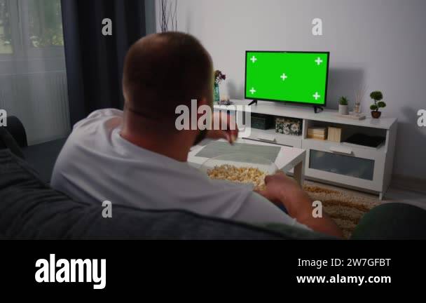Back view Man sitting on the couch in the living room Watching TV with ...