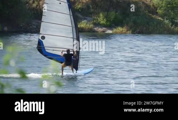 Man on The Windsurf Board With Sail is Floating Fast by Watery Surface ...