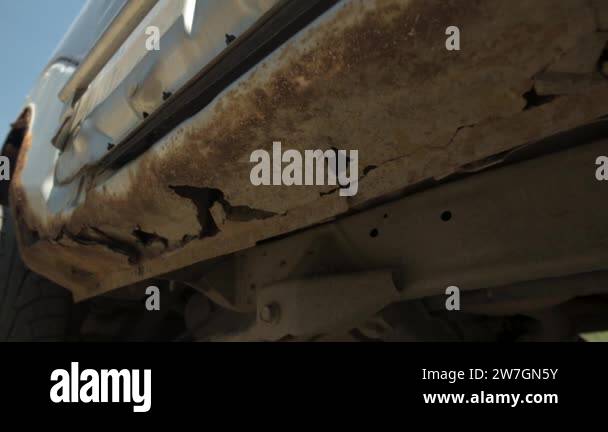 Deep rust on the body of a gray old car. Rust and corrosion hole on old worn out painted metal ...