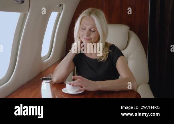 Beautiful successful mature business woman travels on private plane ...