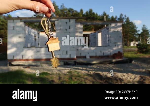 Key ring and pendant of a house and key swinging in the hand against ...