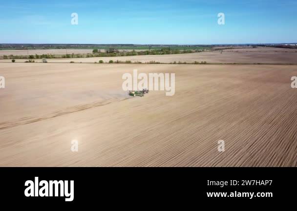 Aerial view of tractor with harrow system plowing ground on cultivated ...