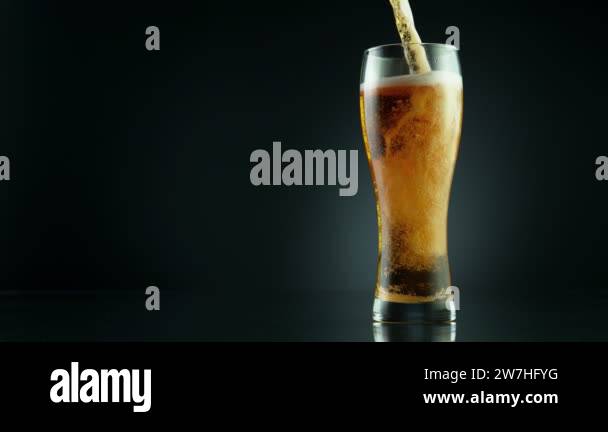 Super slow motion of pouring beer drink into glass, placed on black ...