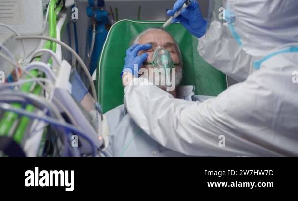 Doctor in personal protective equipment helping old man in ambulance ...