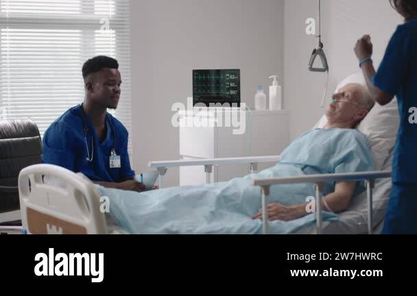 Caring african ethnic medical team at the bedside of an elderly male ...