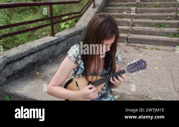 Young beautiful girl playing a musical instrument mandolin while ...