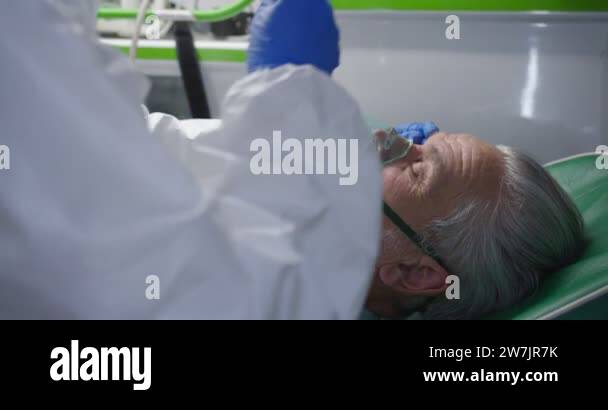 Close up of medic in personal protective equipment resquing old man in ...