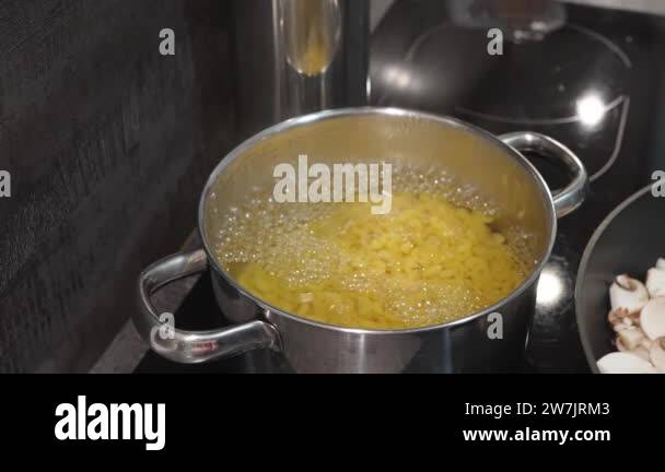 Pasta cooking process. Cook stirs macaroni in boiling water and covers ...