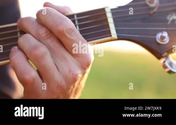 Man plays a guitar and sings outdoor songs at sunset. Hand on the ...