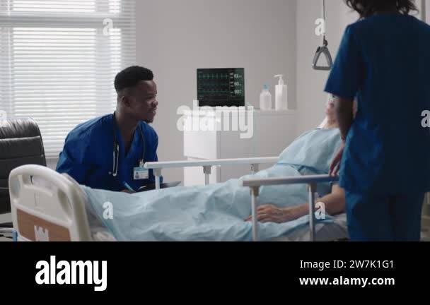 Caring african ethnic medical team at the bedside of an elderly male ...