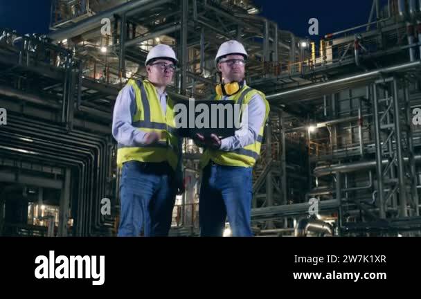 Two engineers are talking inside of the oil refinery plant. Oil ...