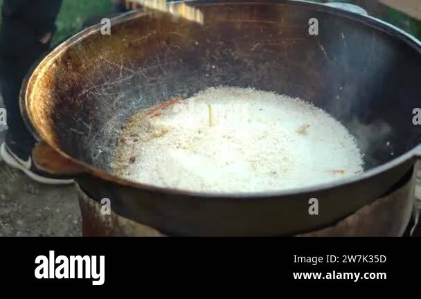 Cooking food over a fire in a cauldron. Cooking rice dishes in the open ...