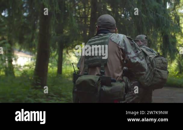 Rearguard soldier with machine gun covering back of squad in forest ...
