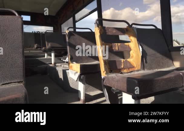 An old rusty broken cabin of an abandoned bus with damaged leather ...