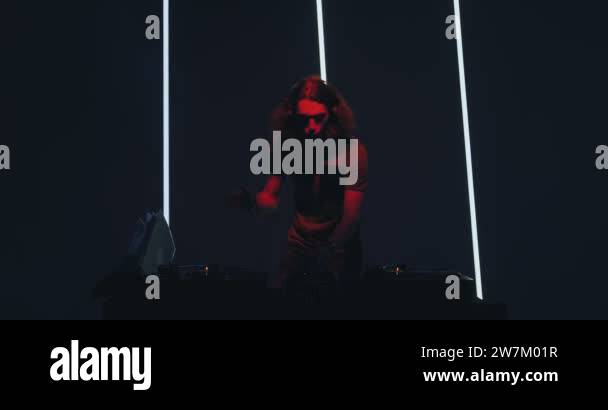 Cool young guy DJ at turntable in disco night club on dance party ...