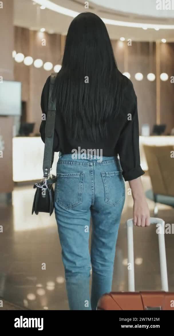 Vertical rear-view slowmo shot of confident young woman carrying ...