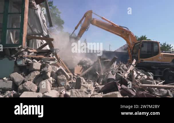 Excavator bucket loads trash and debris from destroyed building into ...