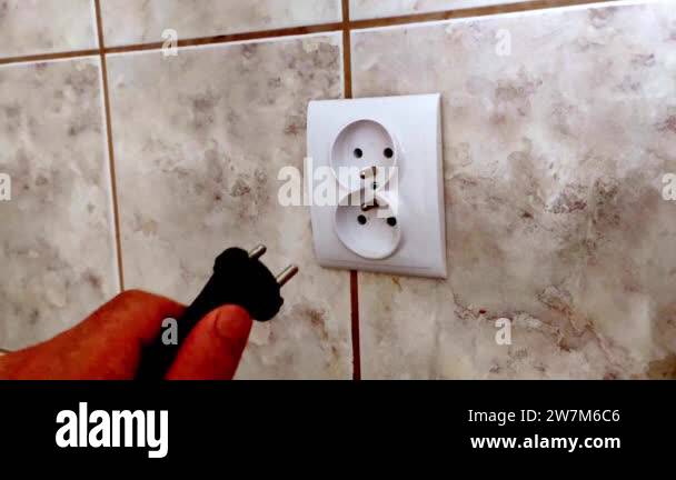 Man's hand puts it in the wall plug socket. Hand plug into electricity ...