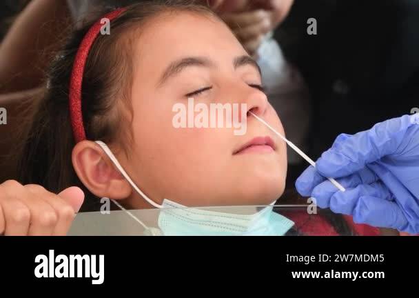 Pediatrician taking nasal mucus test sample from elementary age girls ...