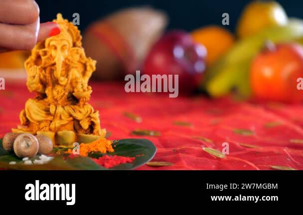 Female hand putting a red Tika on the forehead of Lord Ganesha during a ...