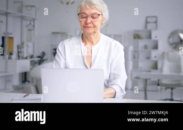 Serious aged lady secretary types on laptop closes computer Stock Video ...