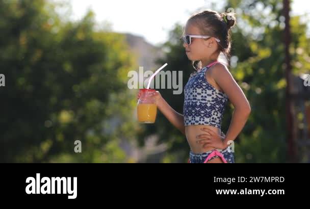 Beautiful little girl, cute toddler with sunglasses is drinking orange ...