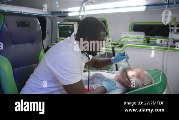 African American paramedic saving life of old man in ambulance. Medic ...