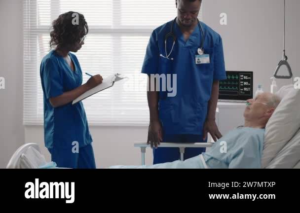 Two black doctors are talking to a patient lying in a hospital room ...