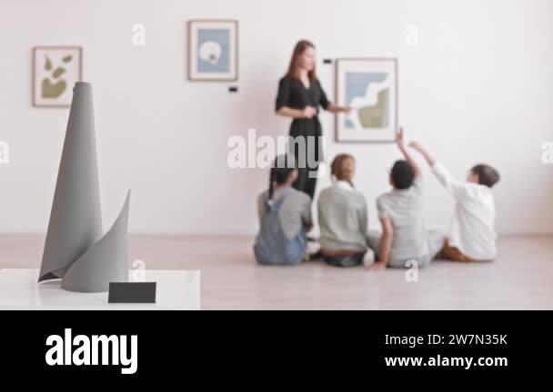 Racking focus from art object on pedestal to children sitting on floor ...