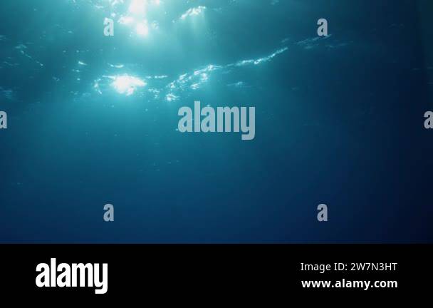 Sunbeams penetrating wavy ocean surfaces. Ocean background light shafts ...