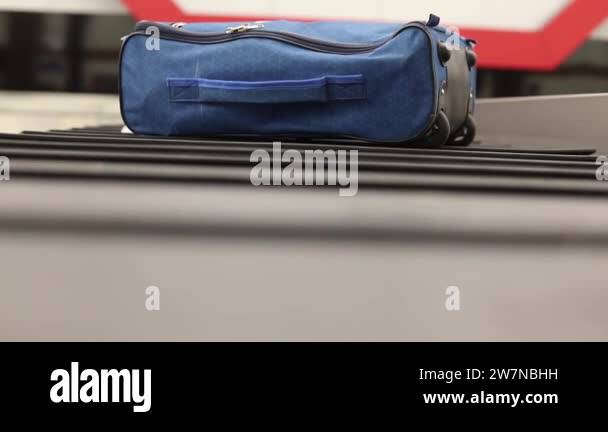 A blue suitcase on a conveyor belt at the international airport ...