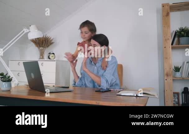 A woman and a child communicate online. A woman and a girl smile and ...