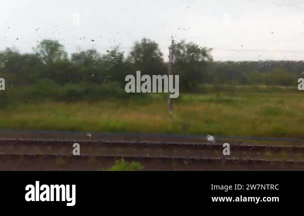 Shooting a rural landscape through the wet glass of a railway carriage ...