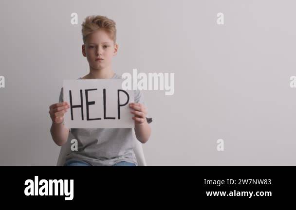 Cry for help. Studio portrait of unhappy teenage boy showing word HEPL ...