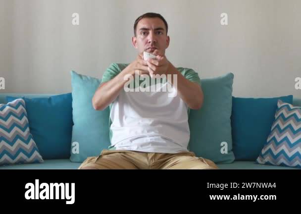 Upset young man tries to turn on tv with broken tv remote control ...