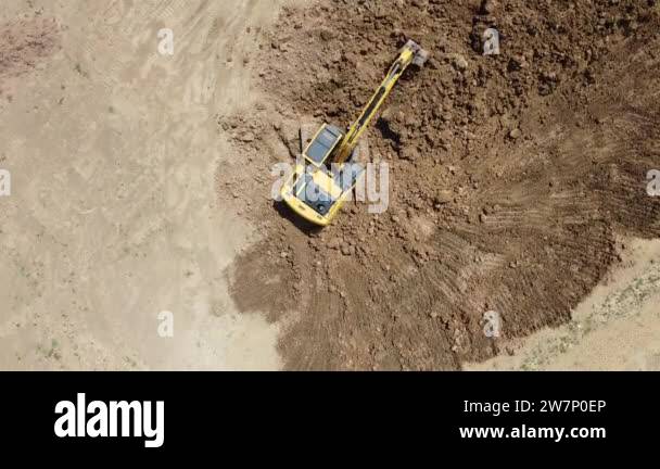 4K on Backhoe or Excavator scraping a layer of soil from bird eye view ...