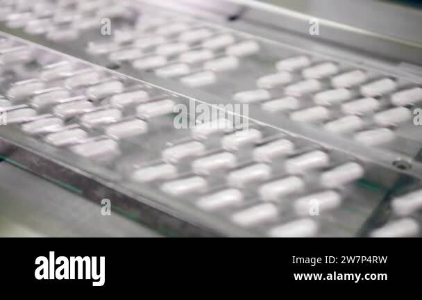 Blister packs with medication capsules moving along the conveyor. Drug ...