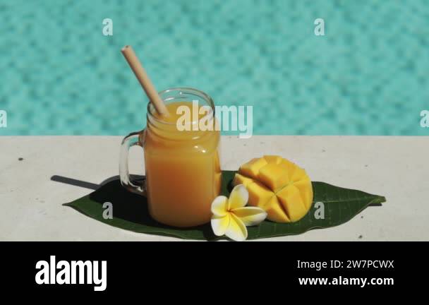 Video footage of glass mason jar with mango juice, bamboo straw, half ...