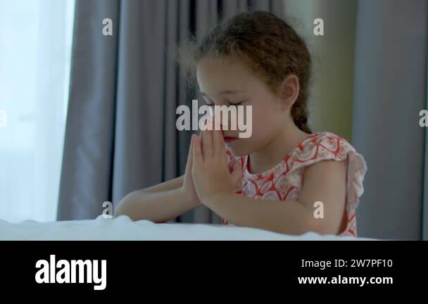 Little girl is praying in her room.Close up portrait of child concept ...