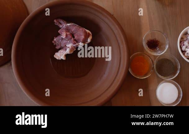 Preparing a lamb, mutton, sheep meat tajine, tagine in a Moroccan clay ...
