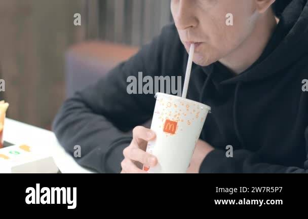 Man student drinks Coca cola at McDonalds fast food restaurant ...