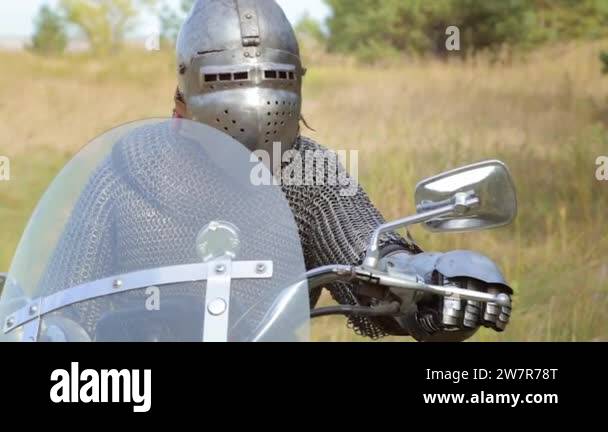 A medieval knight in full armor sits on a motorcycle against the ...