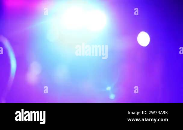 Neon lights on the dance floor. Blurry bokeh. People are jumping on the ...