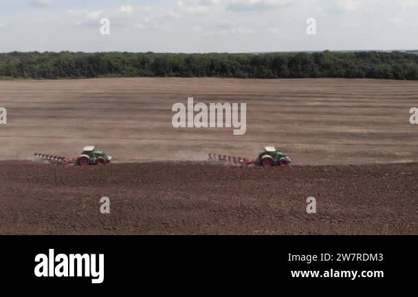 Tractors farming on farm field, kicking up dusty soil into air ...