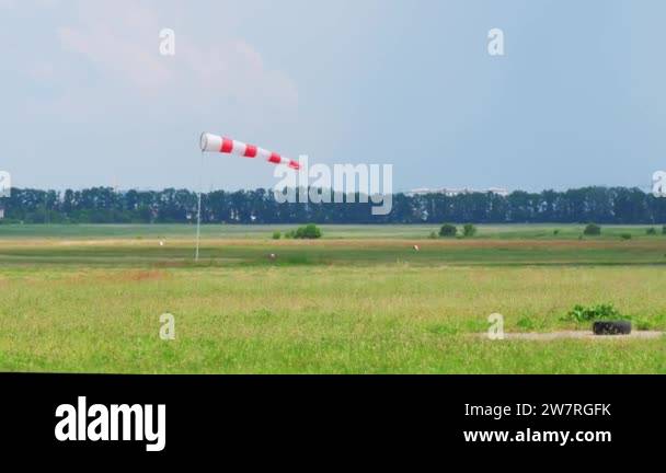 A cone-shaped fabric windsock of red and white color develops in the ...