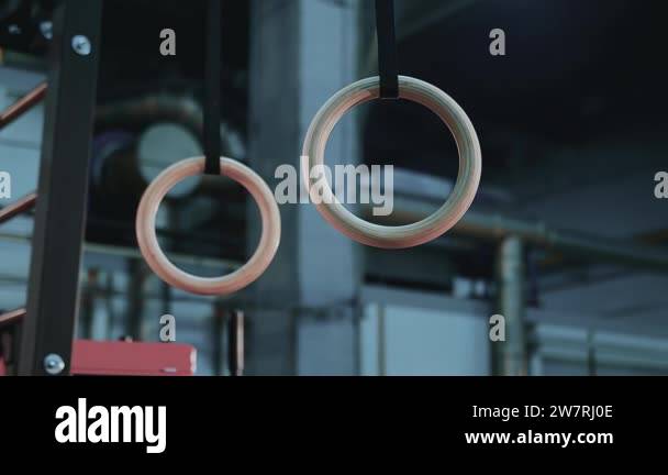 Gymnastic rings on black textile fasteners hang on the horizontal bar ...