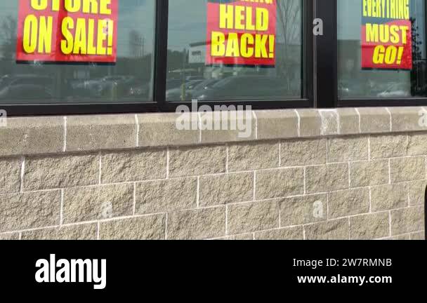 Panning up on signs in the window of a retail store going out of ...
