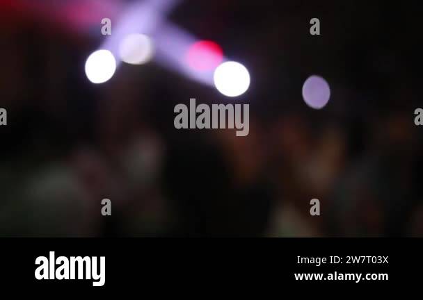 Neon lights on the dance floor. Blurry bokeh. People are jumping on the ...